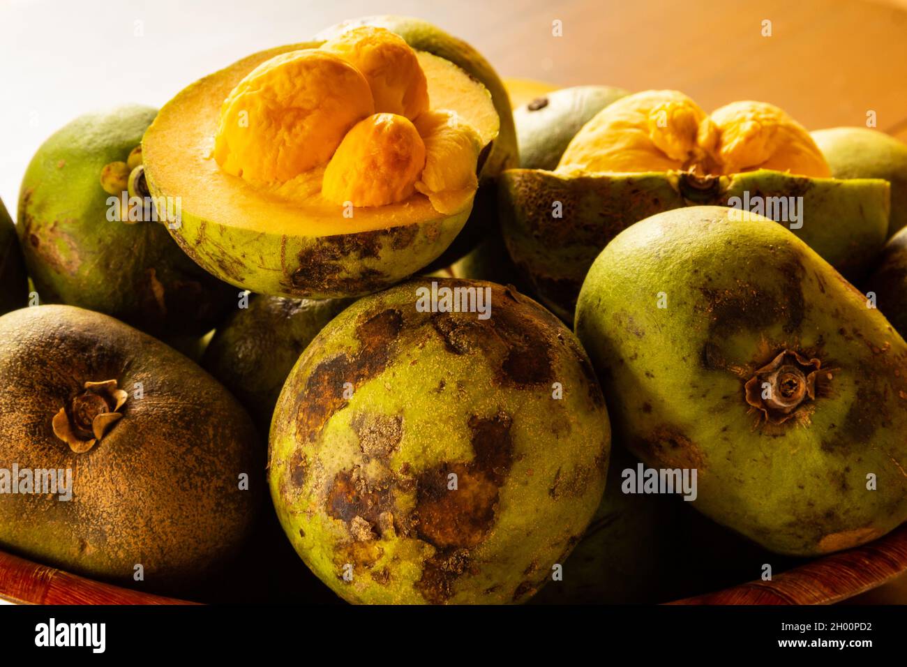 A bowl full of unpeeled pequi fruits with two open fruits Stock Photo ...