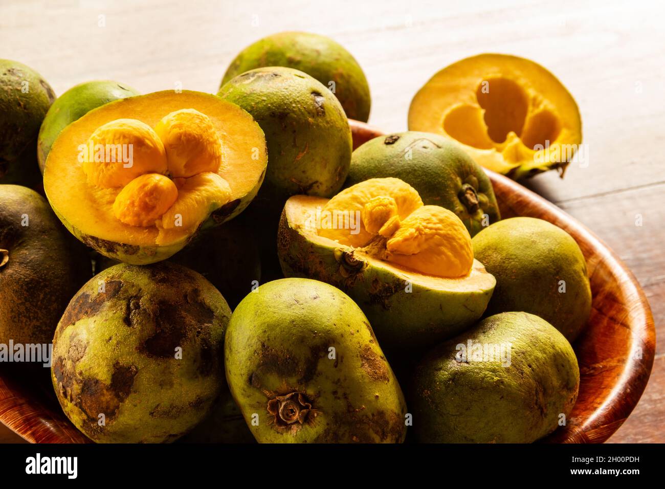 A bowl full of unpeeled pequi fruits with two open fruits Stock Photo ...