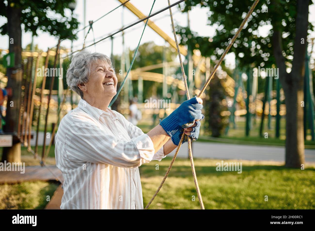 Pretty granny climbing on ropes in summer park Stock Photo - Alamy