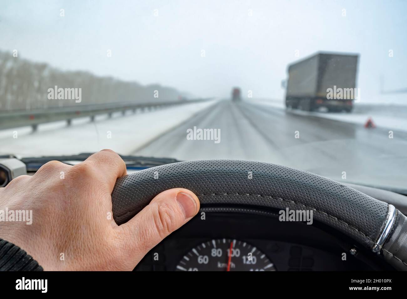 car driver hand on the steering wheel during driving on a slippery road ...