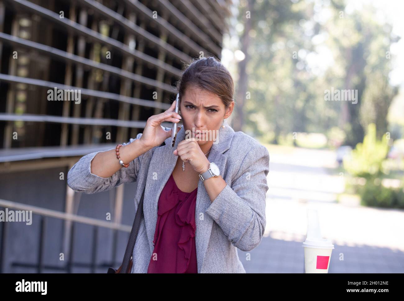 Young business woman talking on mobile phone and coughing in fist in ...