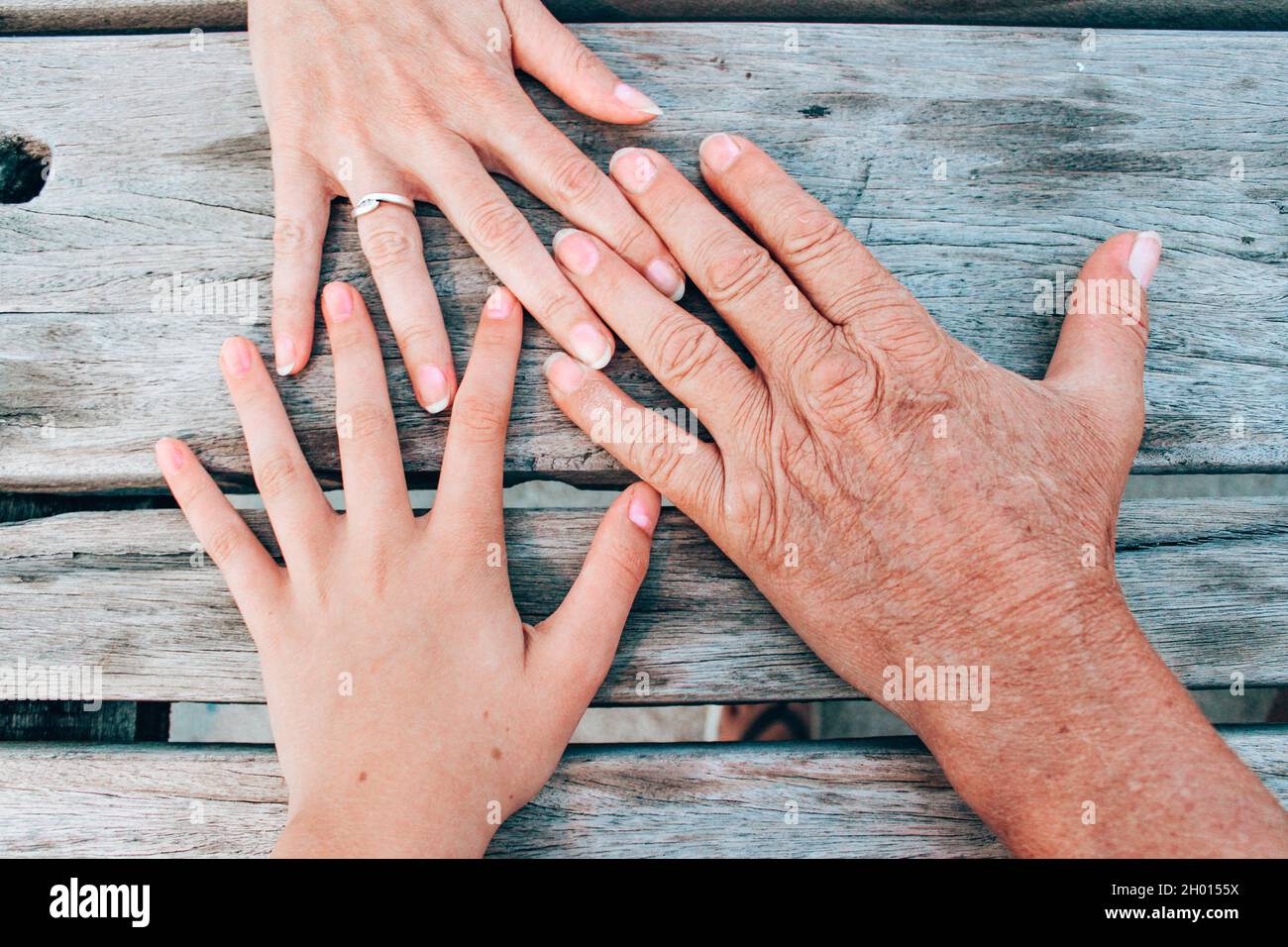 A top view of family members' hands on a wooden table, three ...