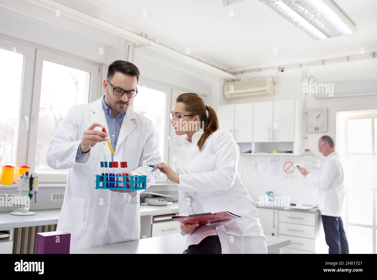 Doctor and nurse holding test tube samples and talking in laboratory ...