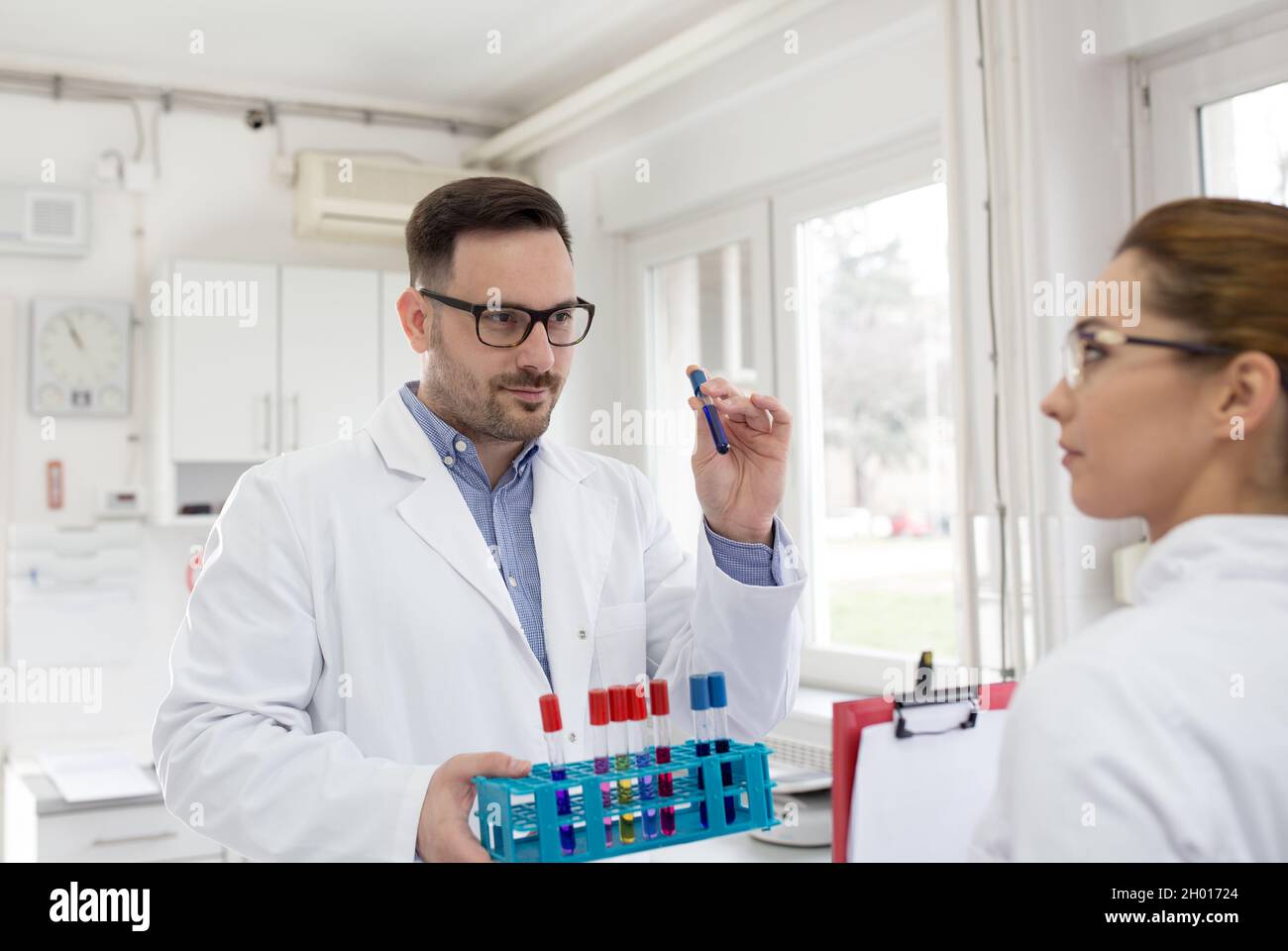 Doctor and nurse holding test tube samples and talking in laboratory ...