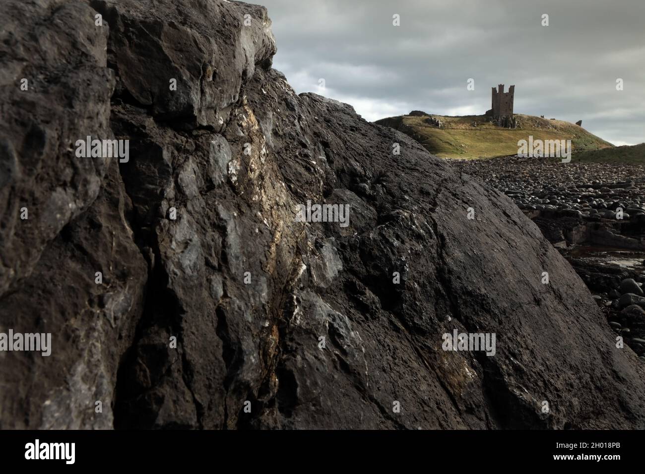 Rocks in Embleton Bay north of the 14th century Dunstanburgh Castle ...