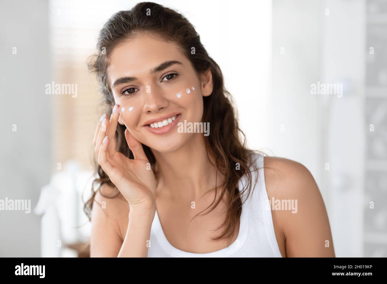 Attractive Female With Moisturizing Facial Cream On Cheeks Posing