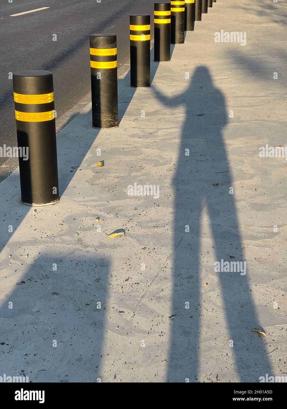 Female silhoutee touching black fencing bollard with yellow reflective ...