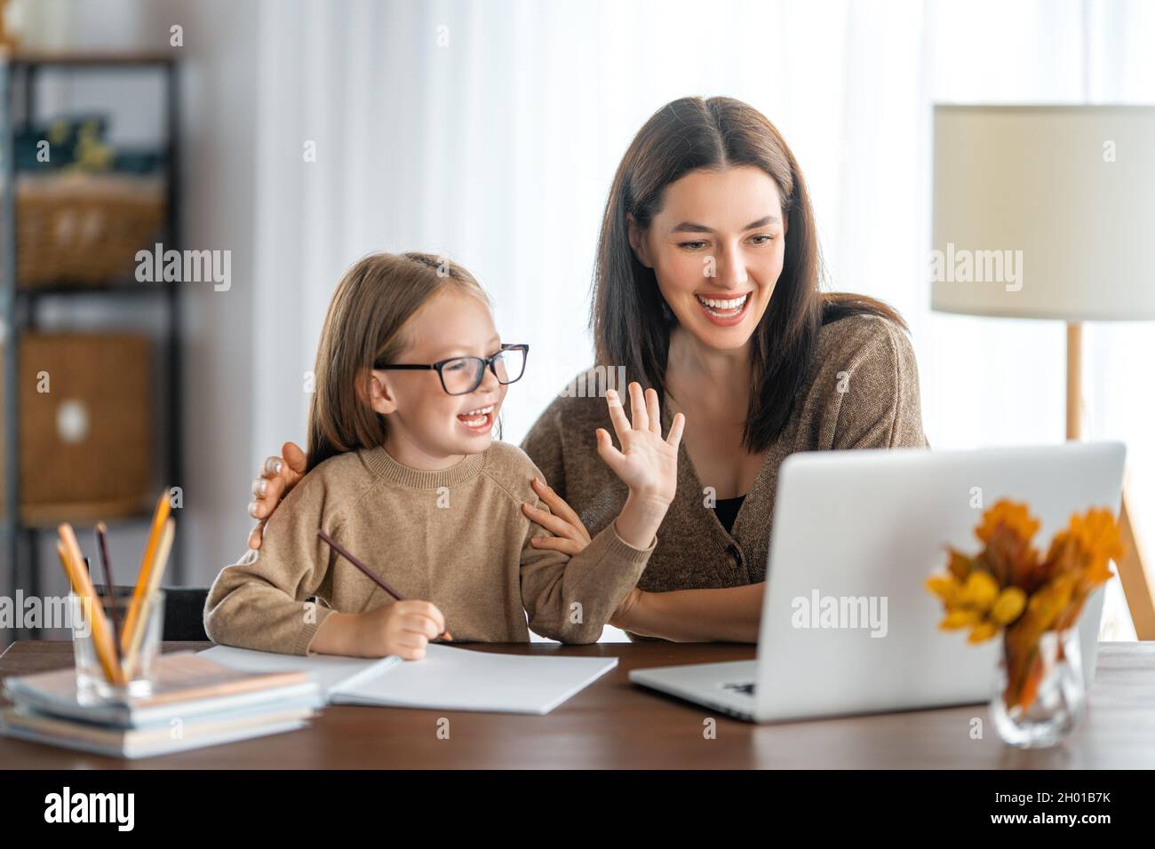 Back to school. Happy child and adult are sitting at desk. Girl doing ...