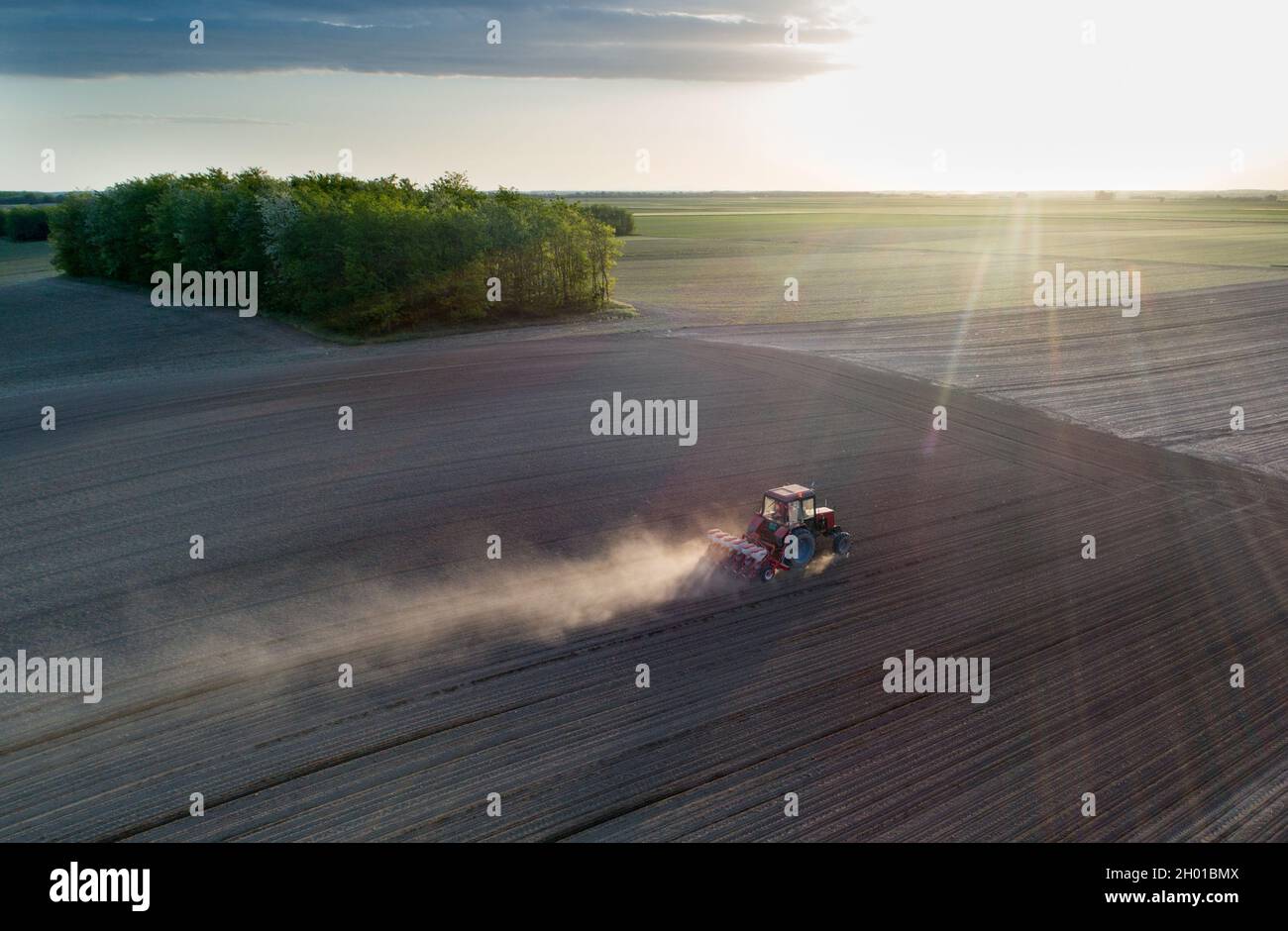 Aerial image of tractor sowing land with corn seeds in spring time at ...