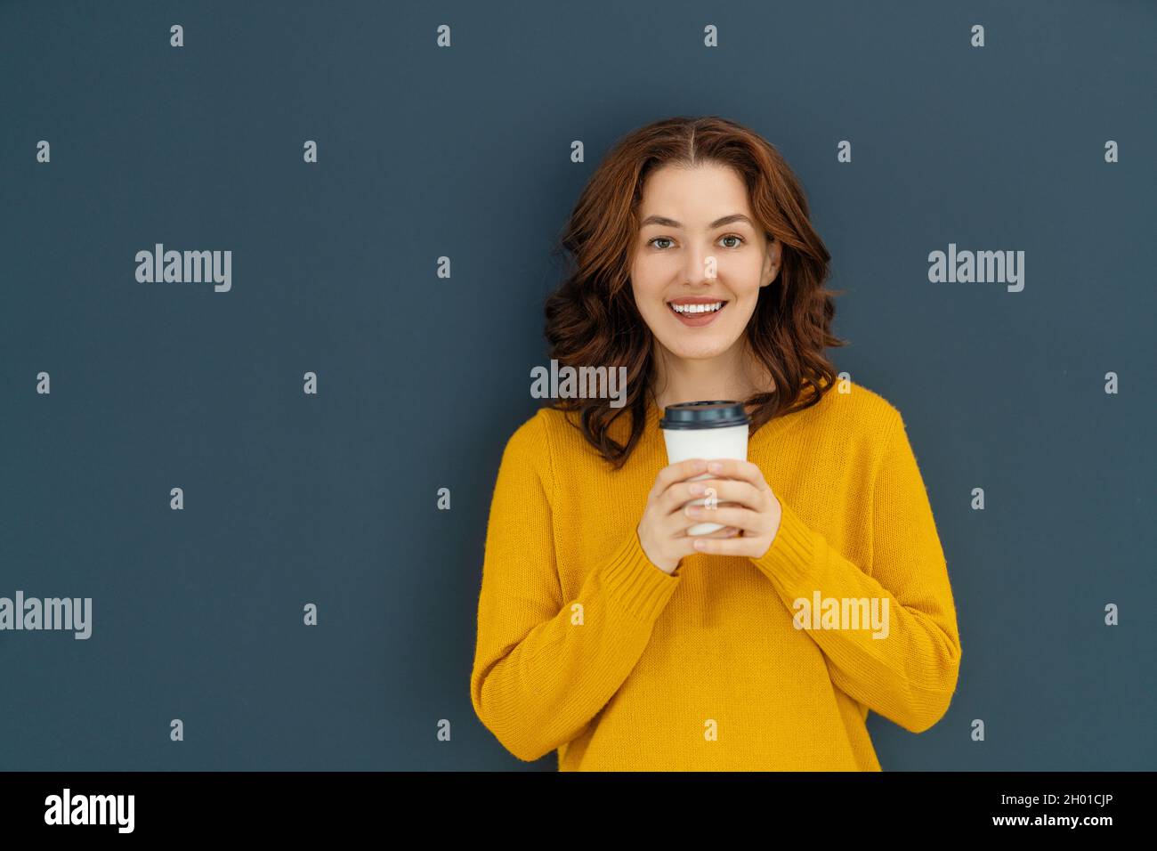 Happy emotional young woman drinking tea on dark wall background Stock ...