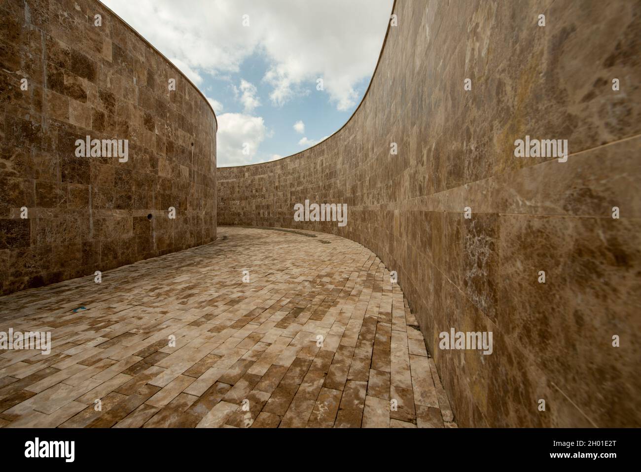 Corridor with high curved walls covered in brown marble tiles and ...
