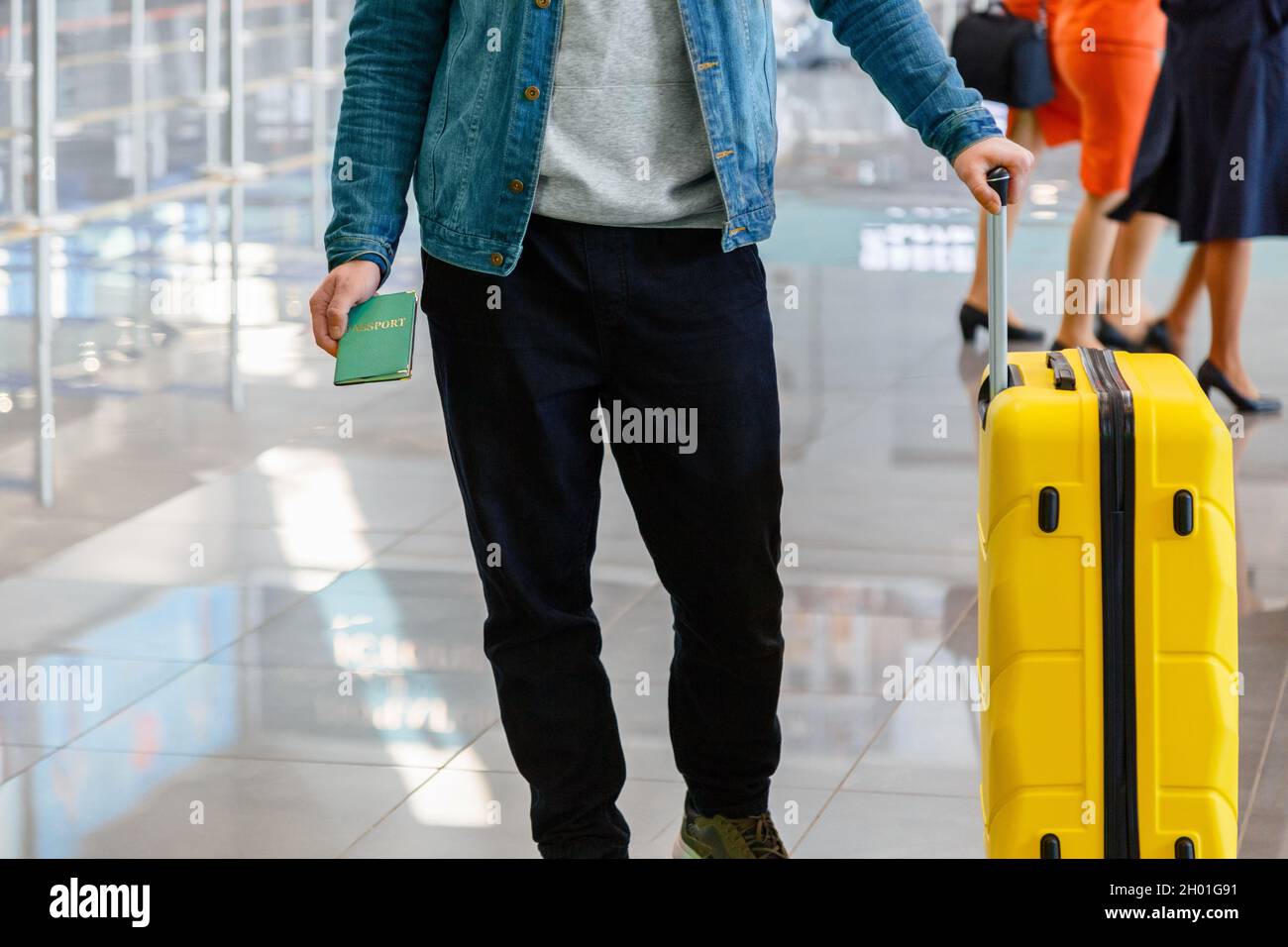 Man holding passport and luggage in his hand large yellow suitcase at ...