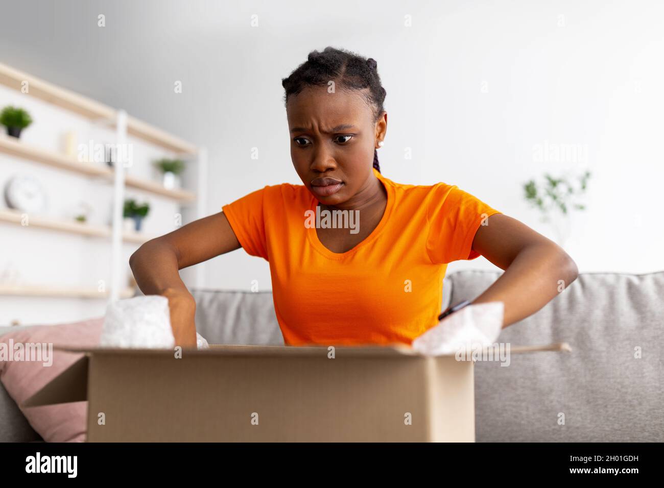 Damaged parcel. Shocked Afro woman unboxing delivery, looking inside ...