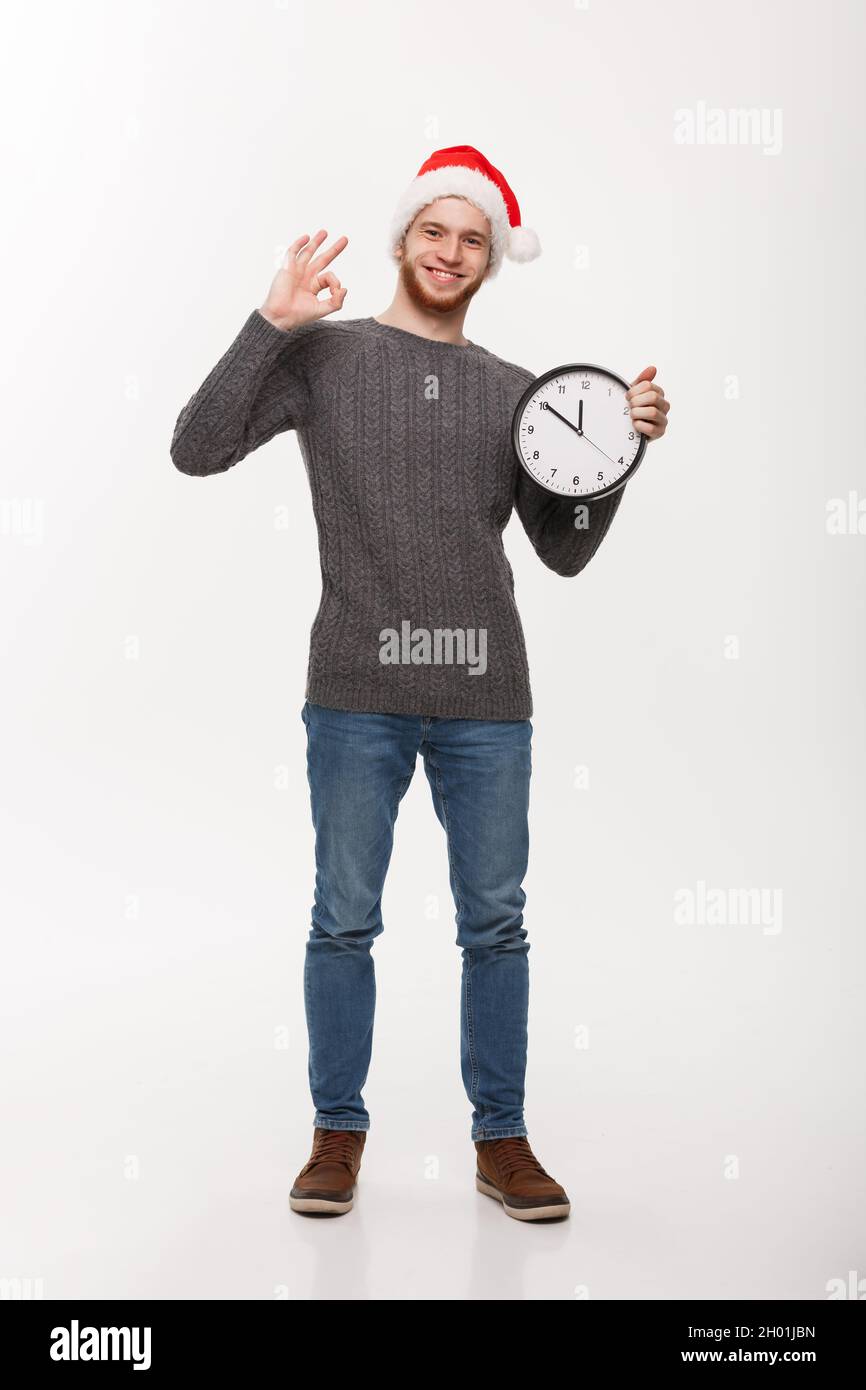 Holiday concept - Young handsome beard man in sweater with white clock ...