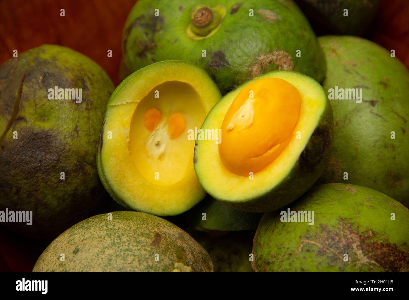 An unpeeled open pequi on a pile of unpeeled pequi Stock Photo - Alamy
