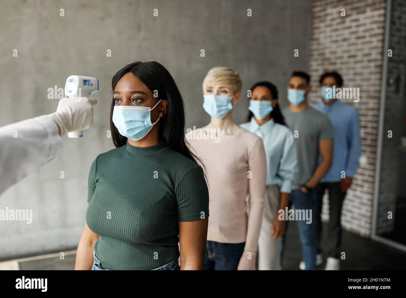 International group of people in protective face masks checking body ...