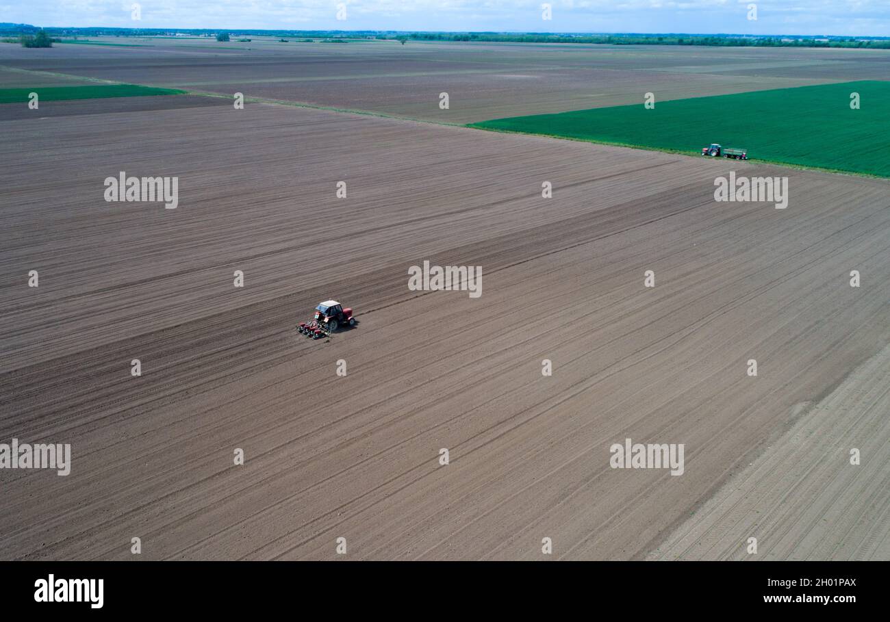 Aerial image of tractor harrowing field in spring time shoot from drone ...
