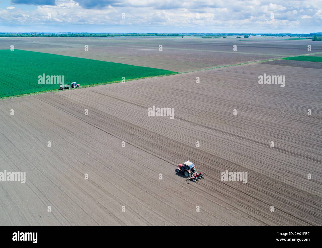 Aerial image of tractor harrowing field in spring time shoot from drone ...