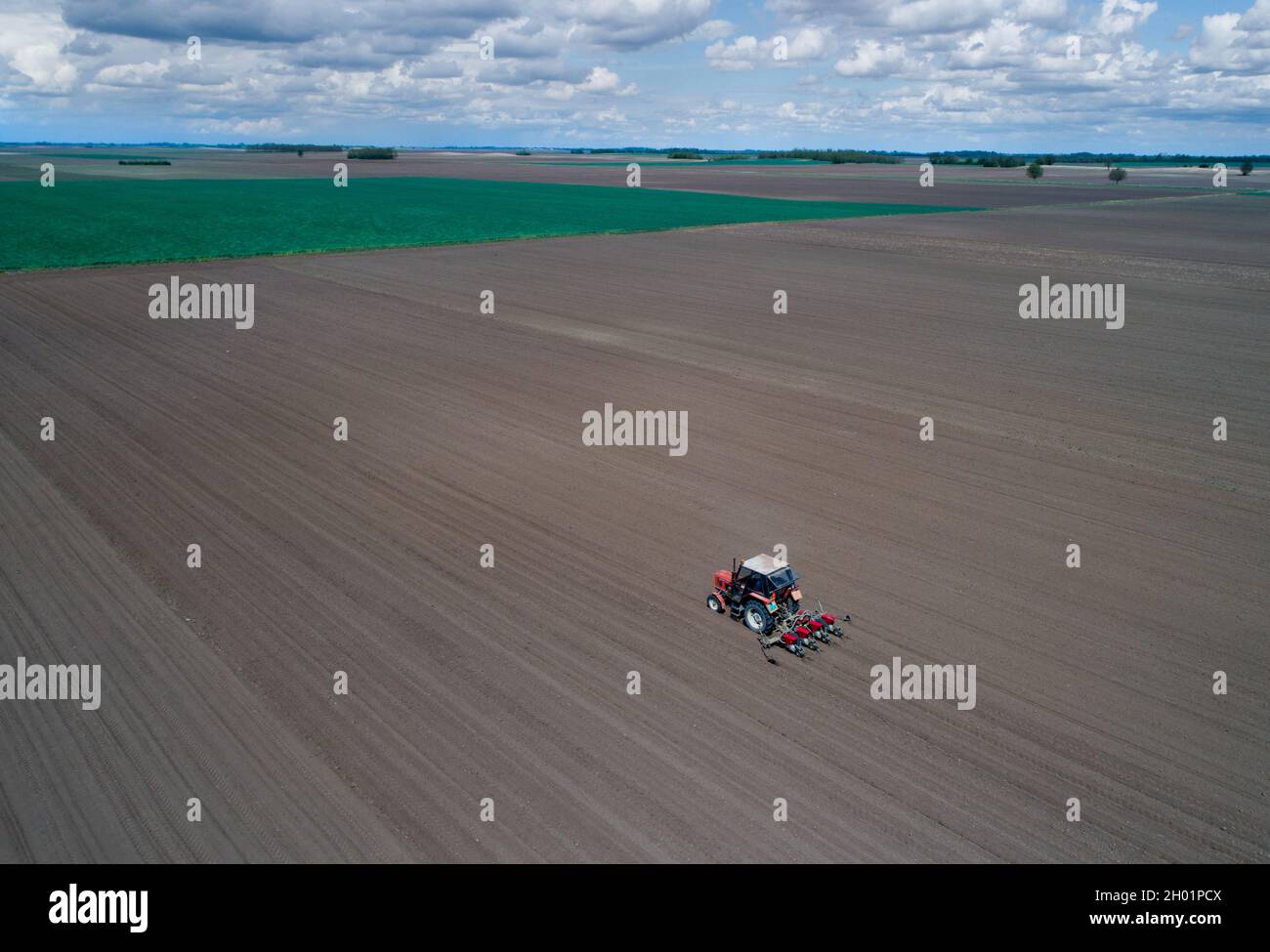 Aerial image of tractor harrowing field in spring time shoot from drone ...