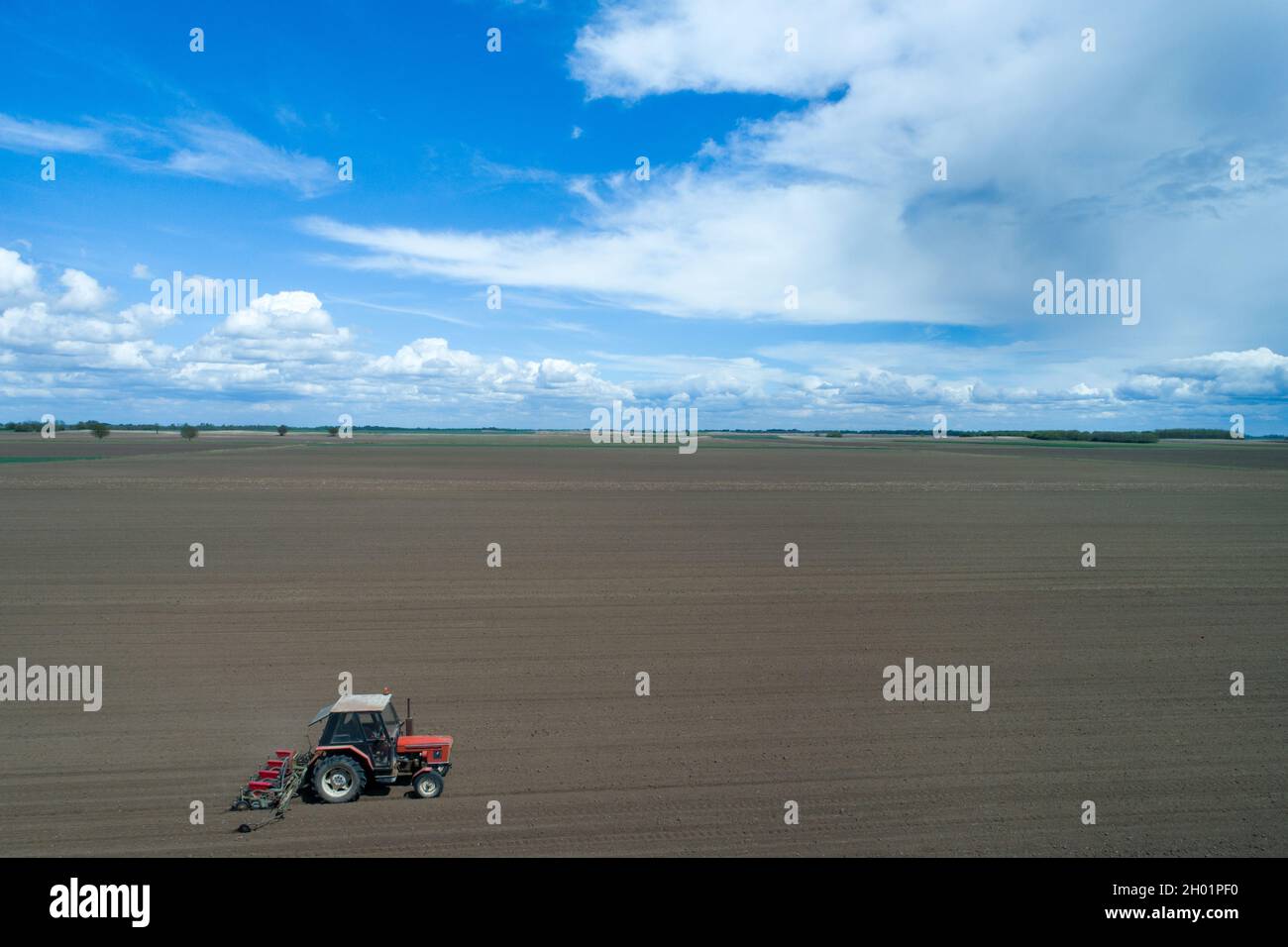 Aerial image of tractor harrowing field in spring time shoot from drone ...