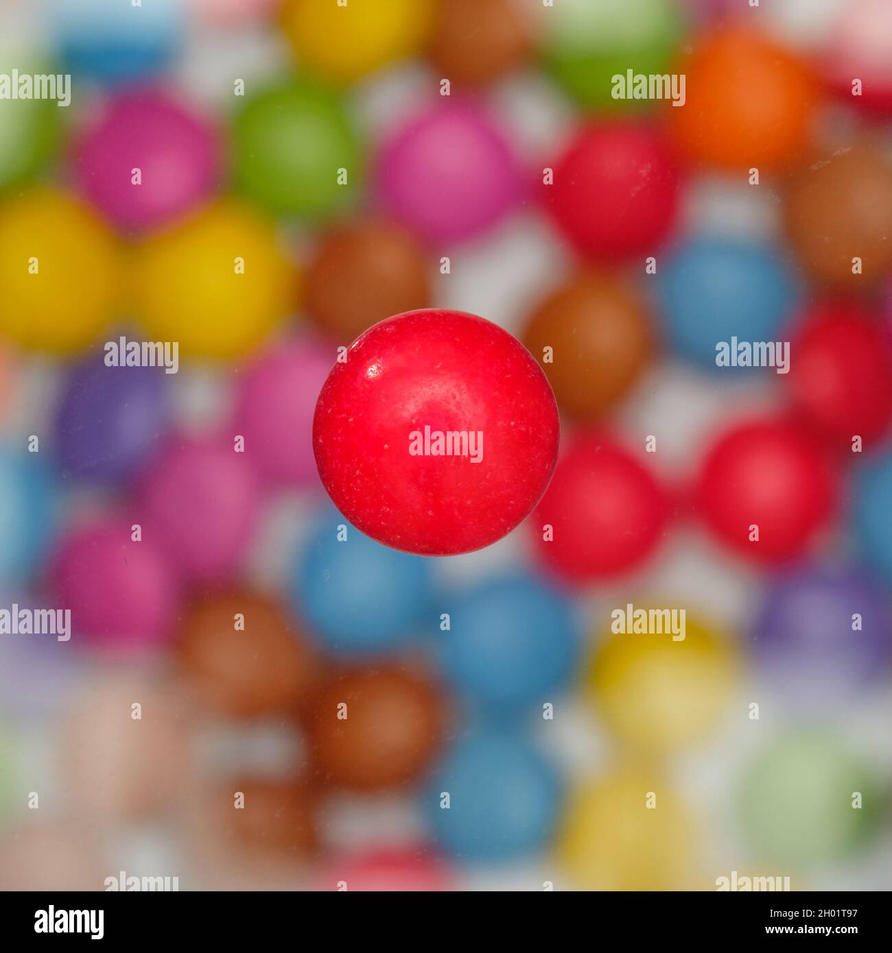 A red chocolate candy isolated on a blurred heap of candies Stock Photo ...