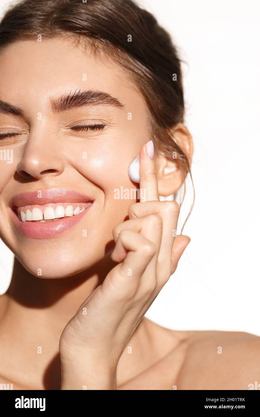 Vertical portrait of smiling happy woman cleansing skin, washing her ...