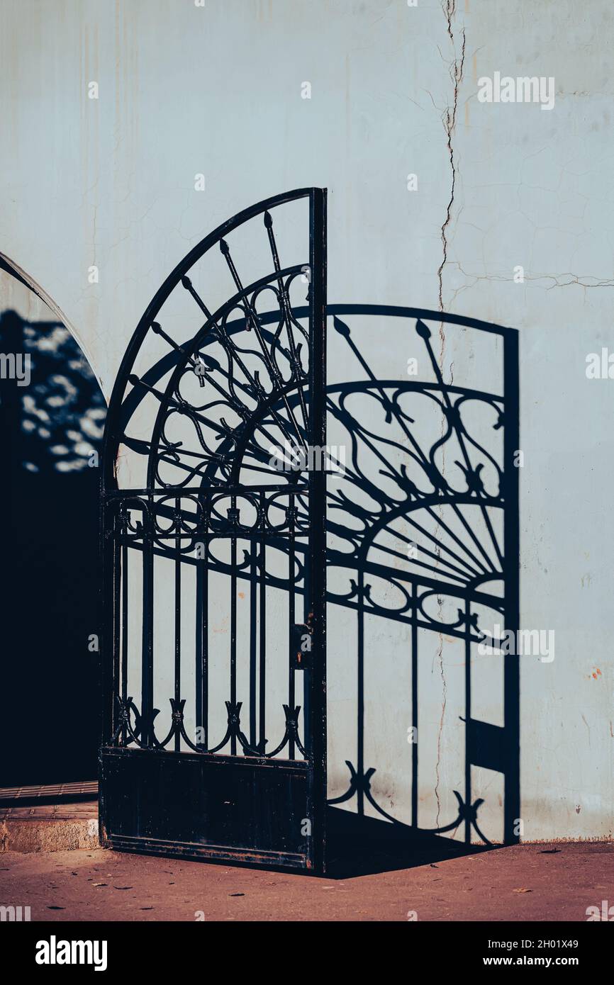 Iron forged openwork gates and contrast shadow on old wall. Abstract ...