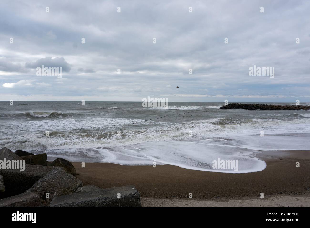 A beautiful view of a beach with wavy sea on a cloudy day Stock Photo ...