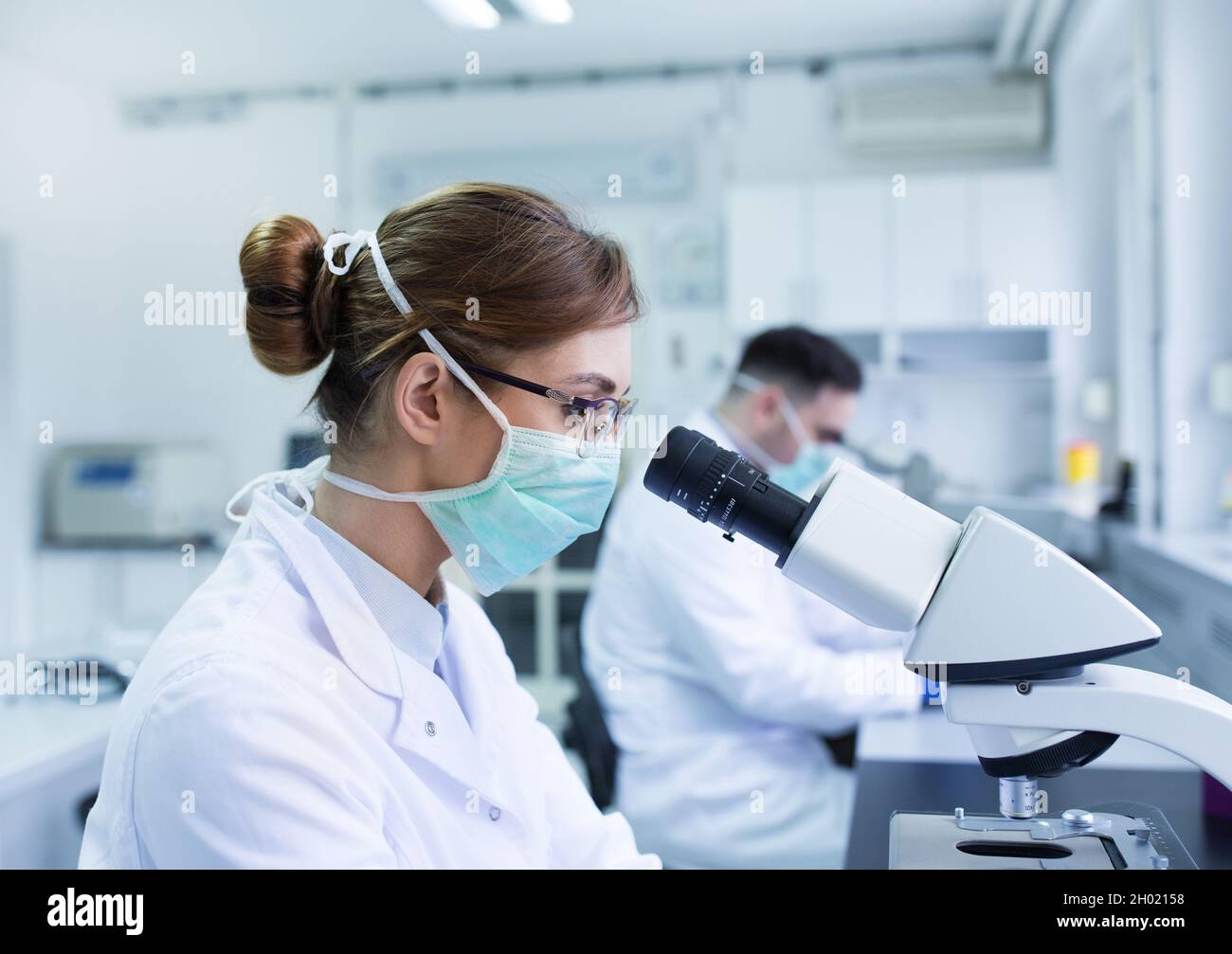 Team of experienced biologists working on microscopes in laboratory ...