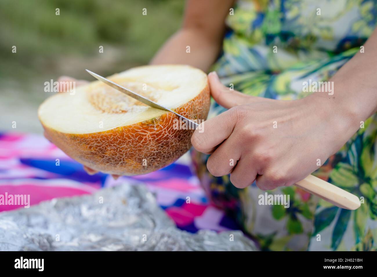 Close up on hands of unknown caucasian woman cutting melon in summer ...