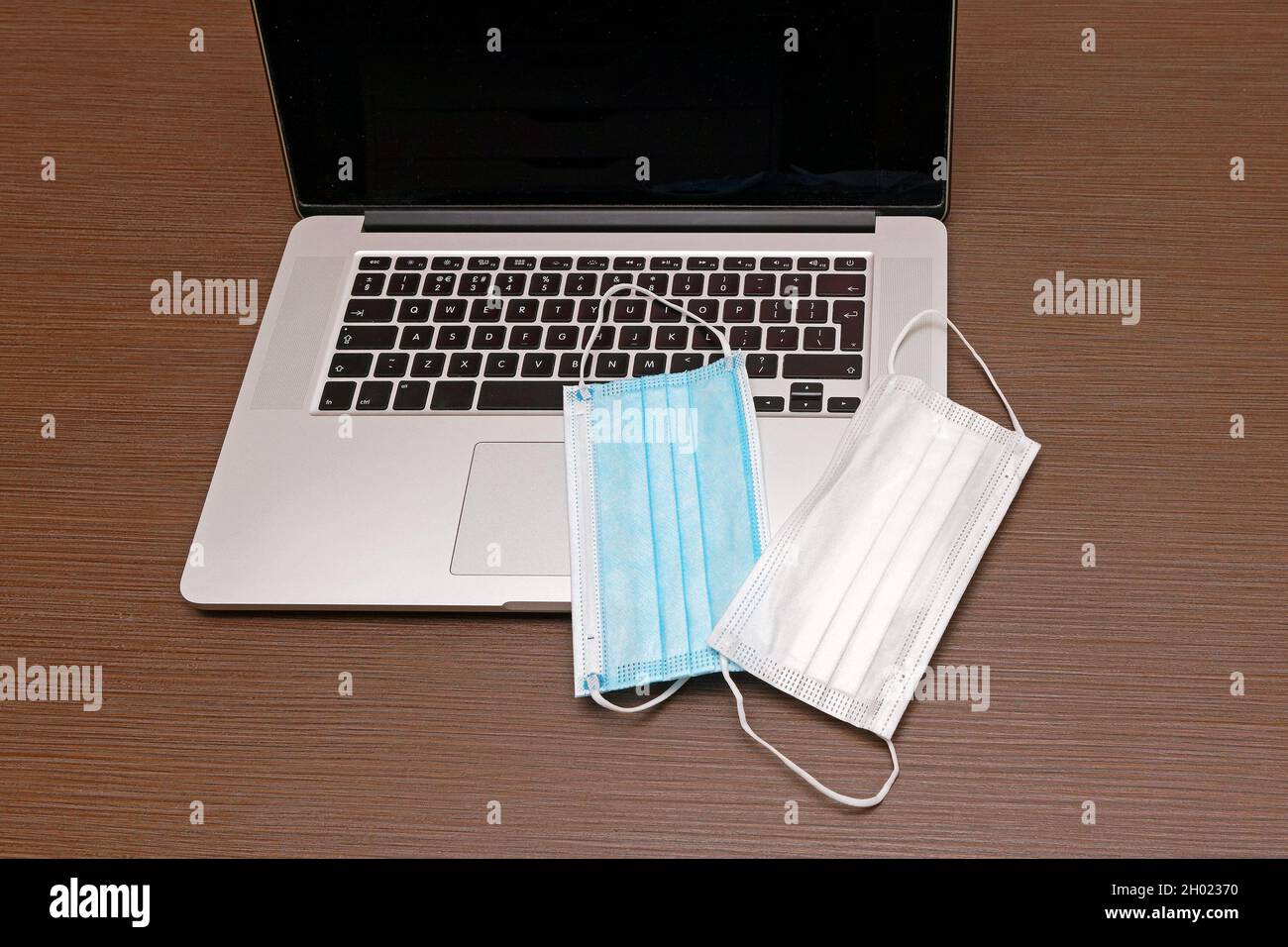 Open laptop with face masks on keyboard for employees working inside ...