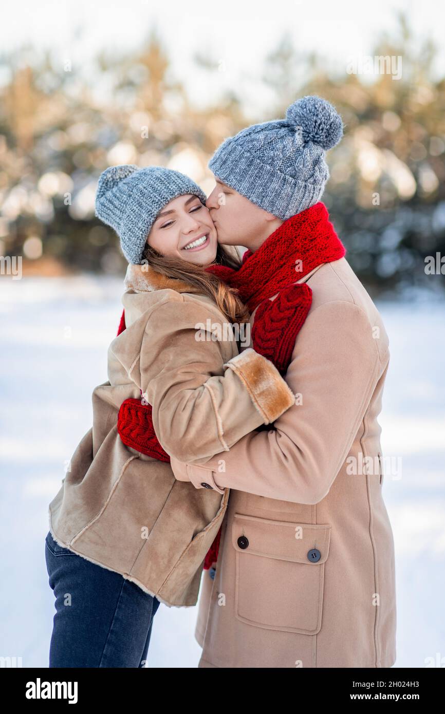 Closeup of young loving man hugging and kissing his smiling pretty ...