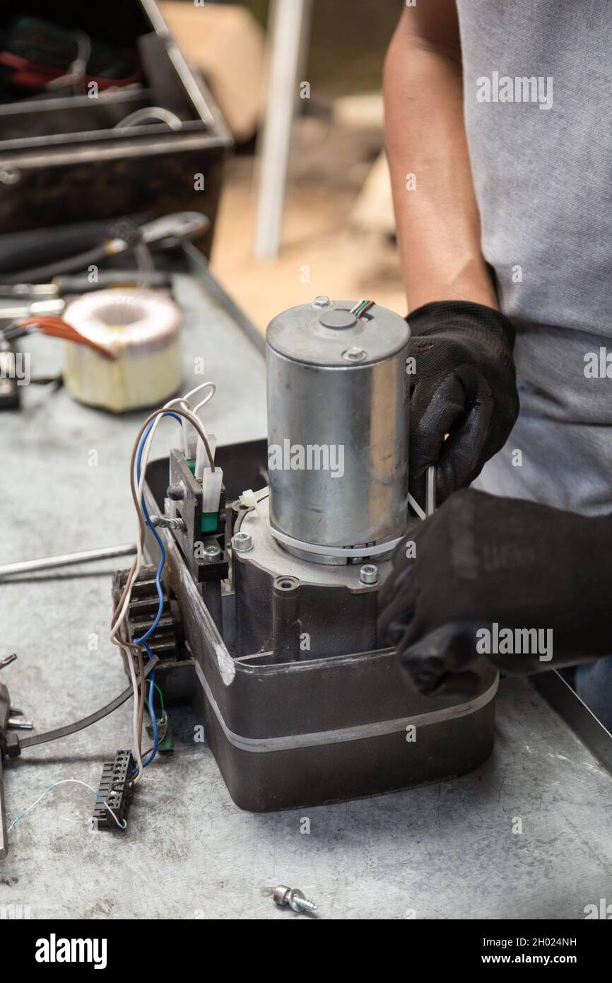 hand of a person repairing a modern metal object that is on his ...