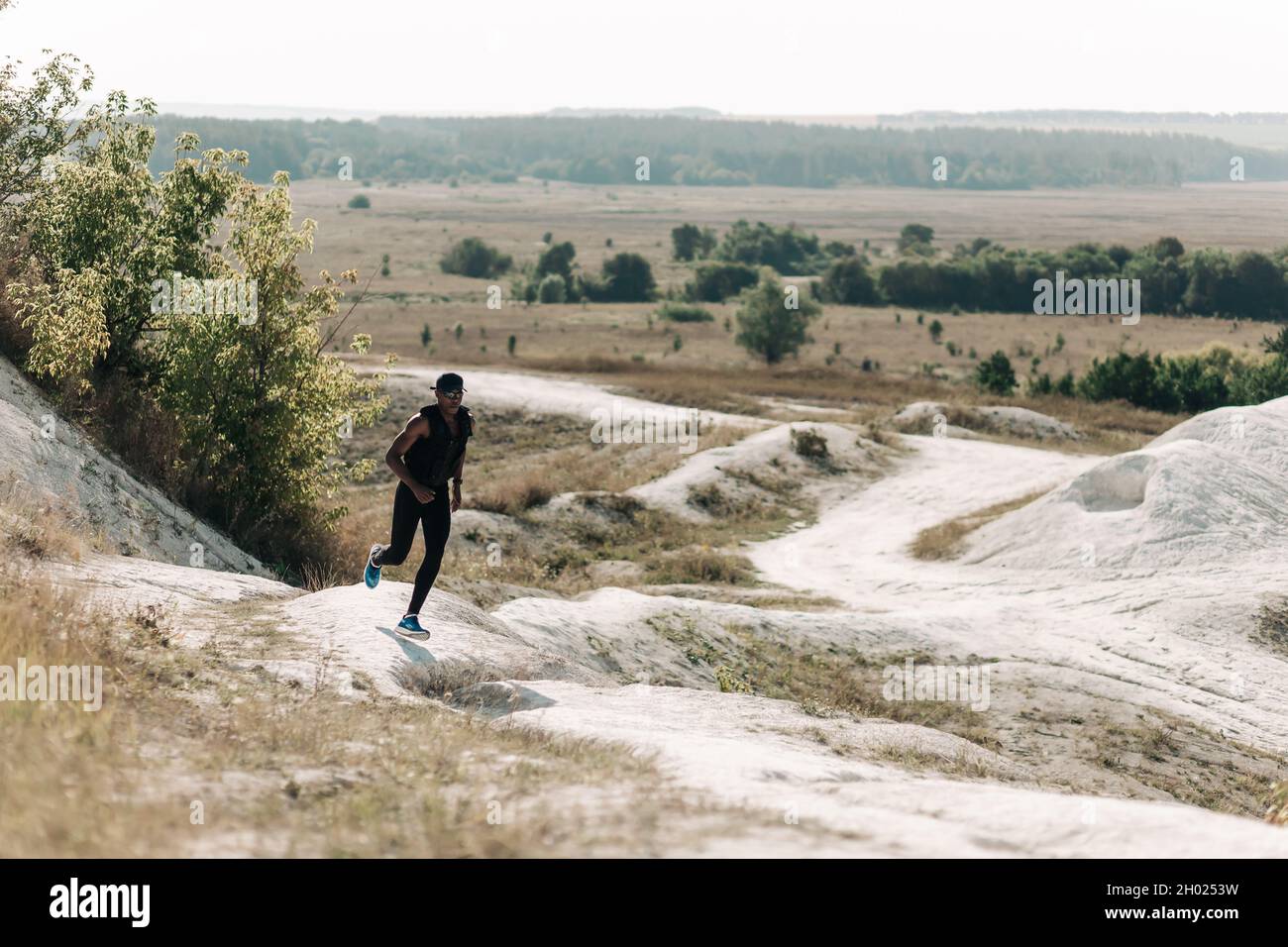 African American fitness men, in sportswear, running along the rocky ...