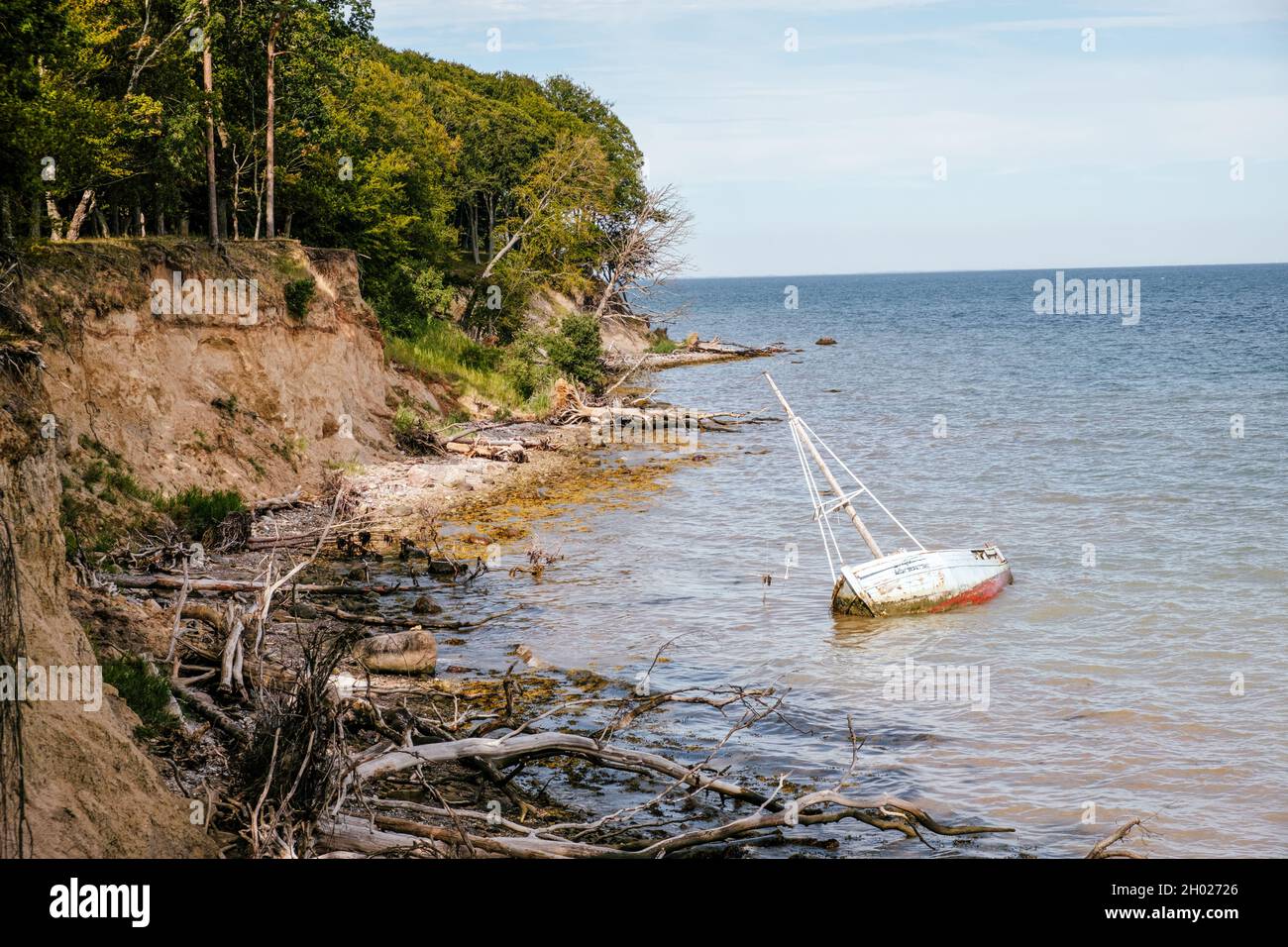 An old crashed boat in the sea surrounded by a park covered in greenery ...