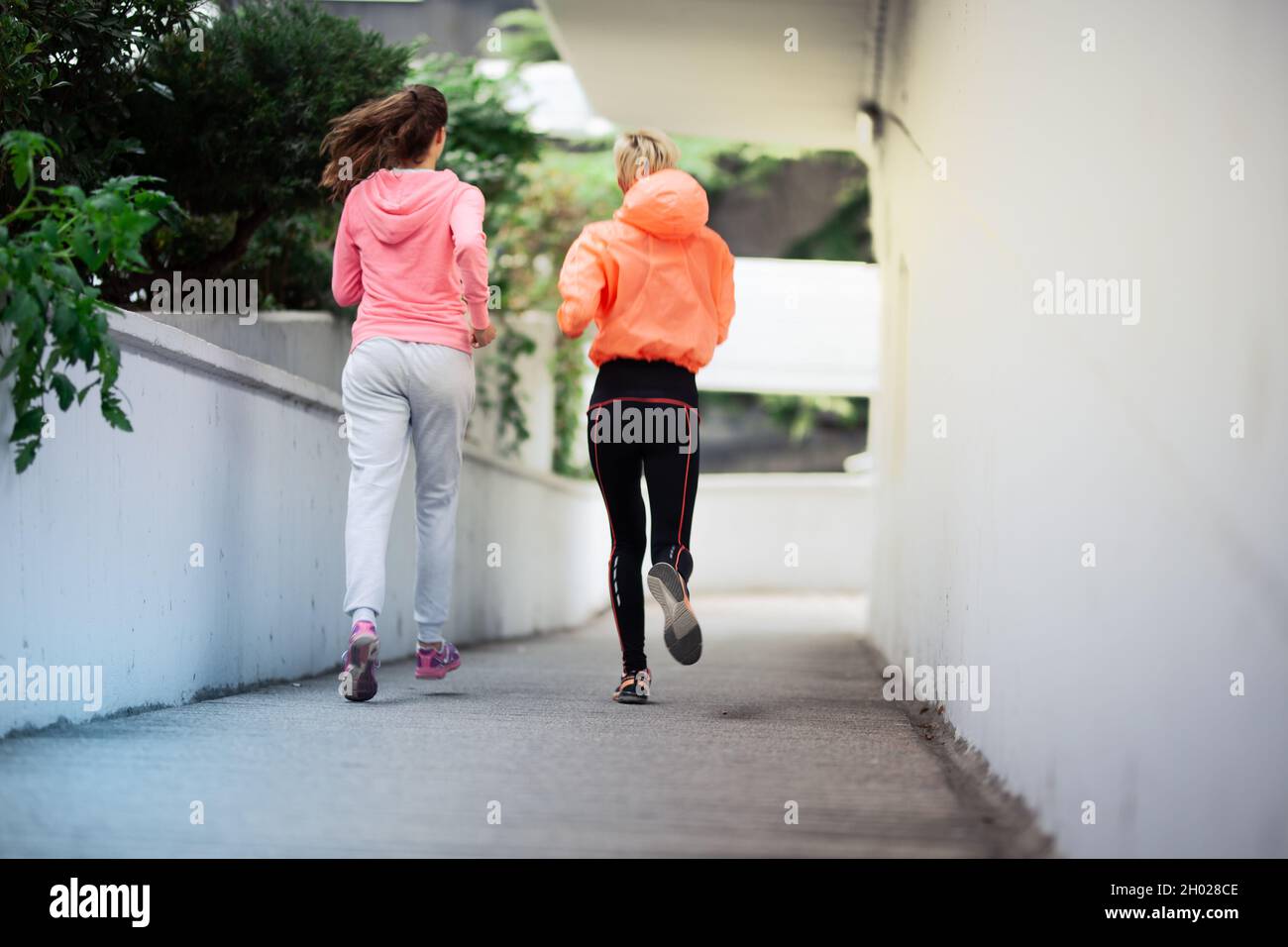 Two girls running outside on a concrete pathway. Motion blur photo ...