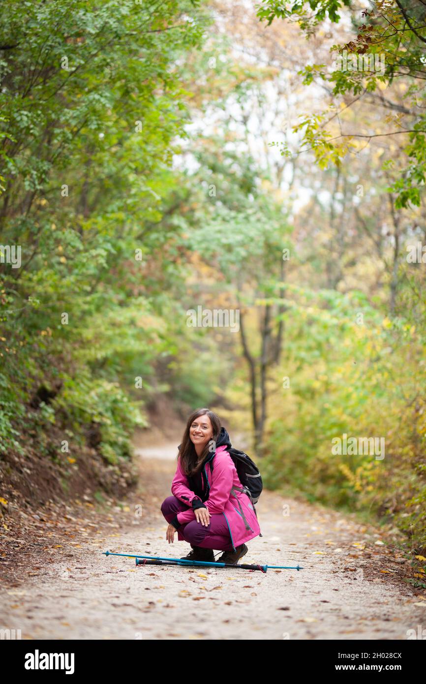Hiker girl crouching on a trail in the mountains. Backpacker with pink ...