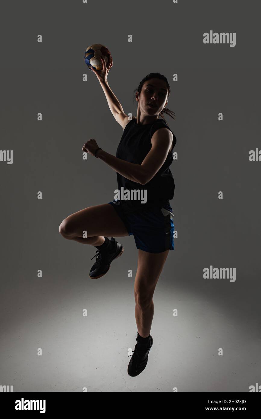 Handball player posing on gray background. Girl jumping with ball Stock ...