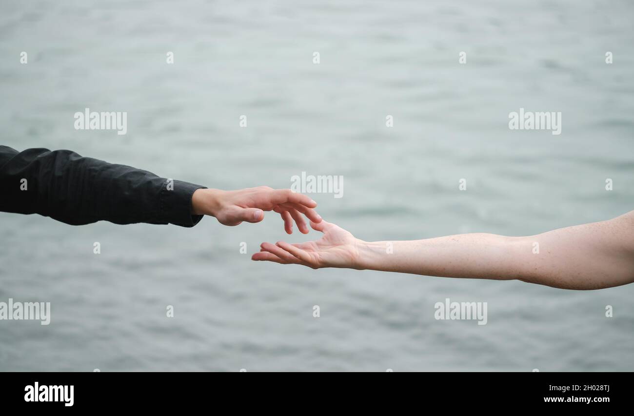 Man and woman hands reaching out each other, holding hands over grey ...
