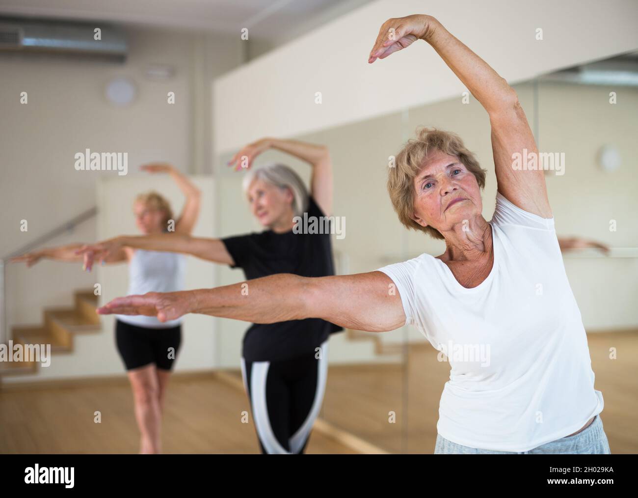 Senior lady learning classic dance moves during group class Stock Photo ...