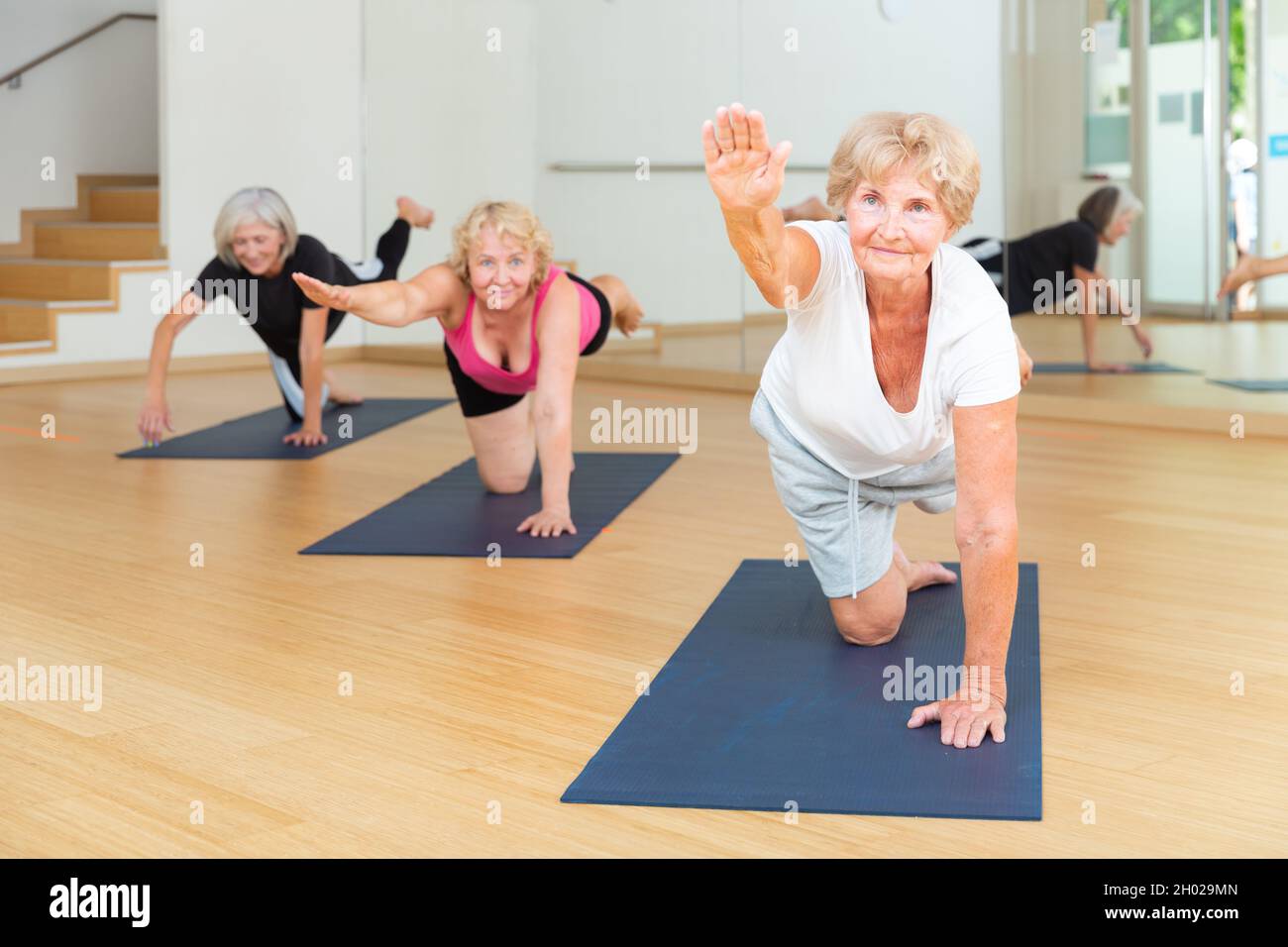 Senior woman practicing Balancing Table pose during group yoga training ...
