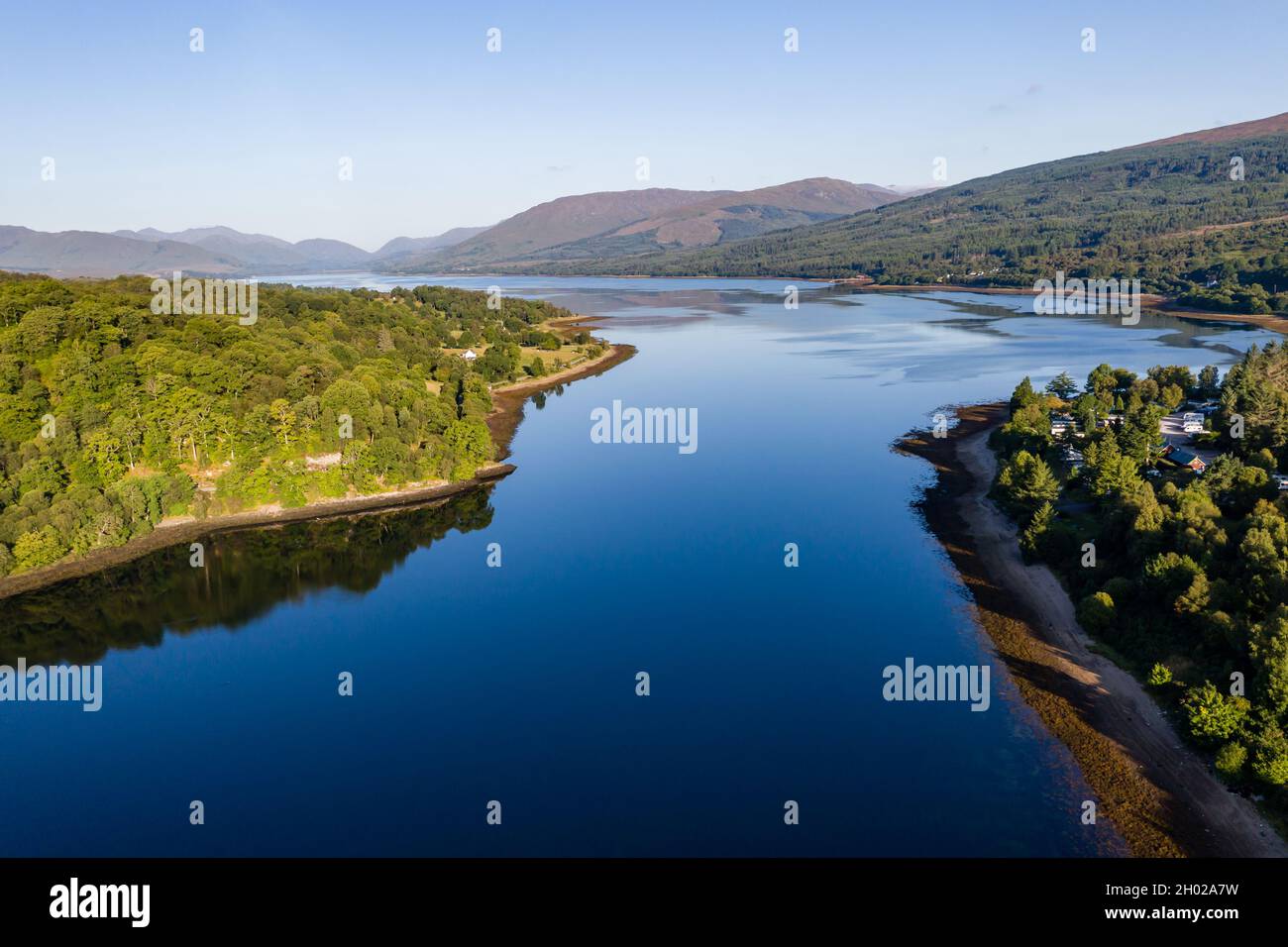 Aerial view of a tranquil Scottish loch in the early morning sunshine ...