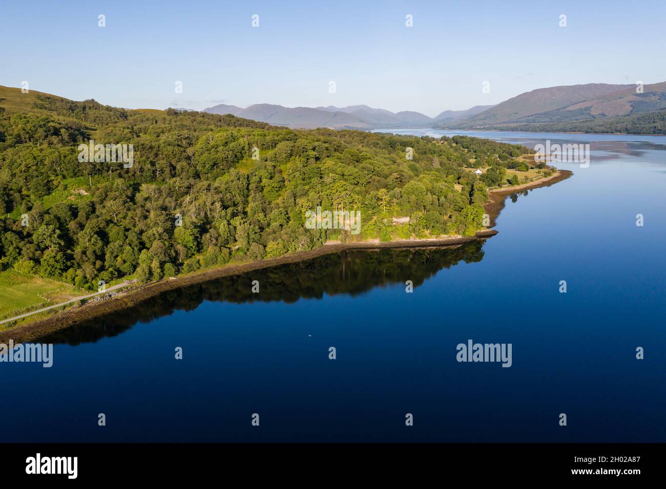Aerial view of a tranquil Scottish loch in the early morning sunshine ...