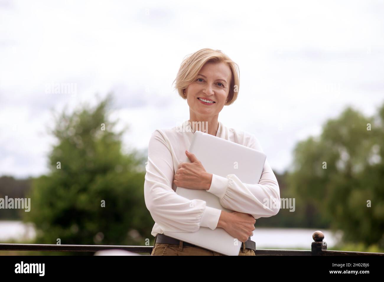 Pleased elegant lady with a notebook computer looking ahead Stock Photo ...