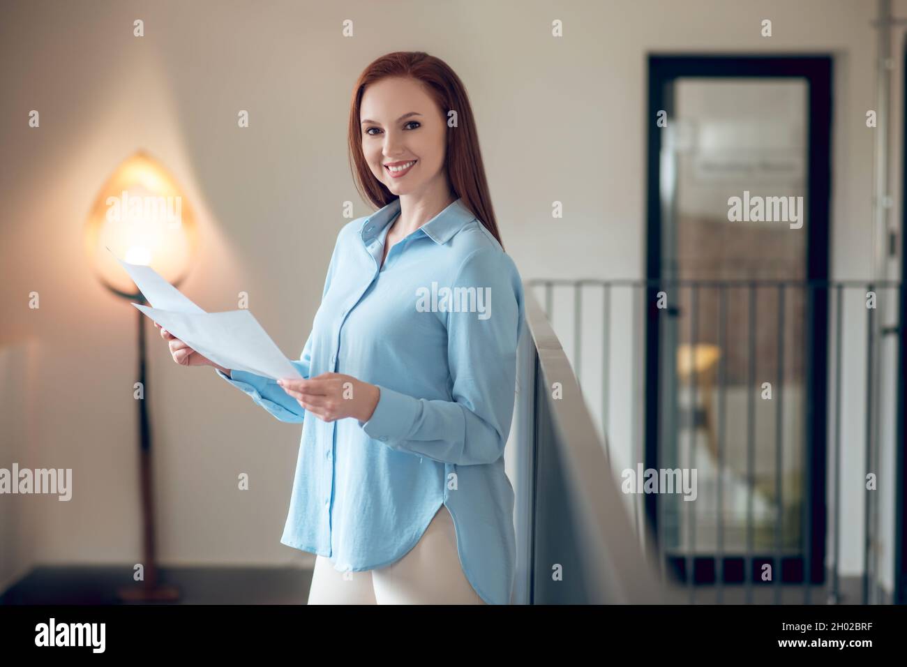 Smiling woman with blueprints in illuminated room Stock Photo - Alamy