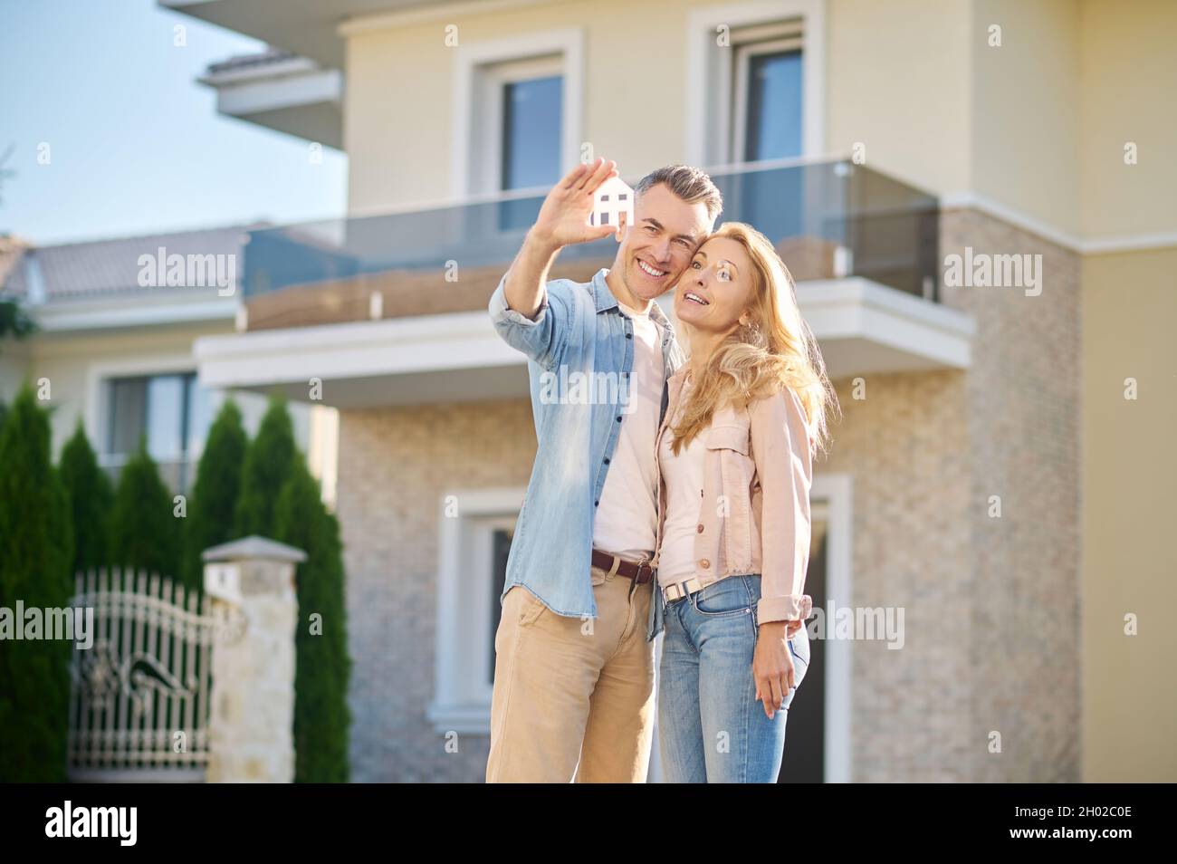 Man with house sign hugging his wife Stock Photo - Alamy