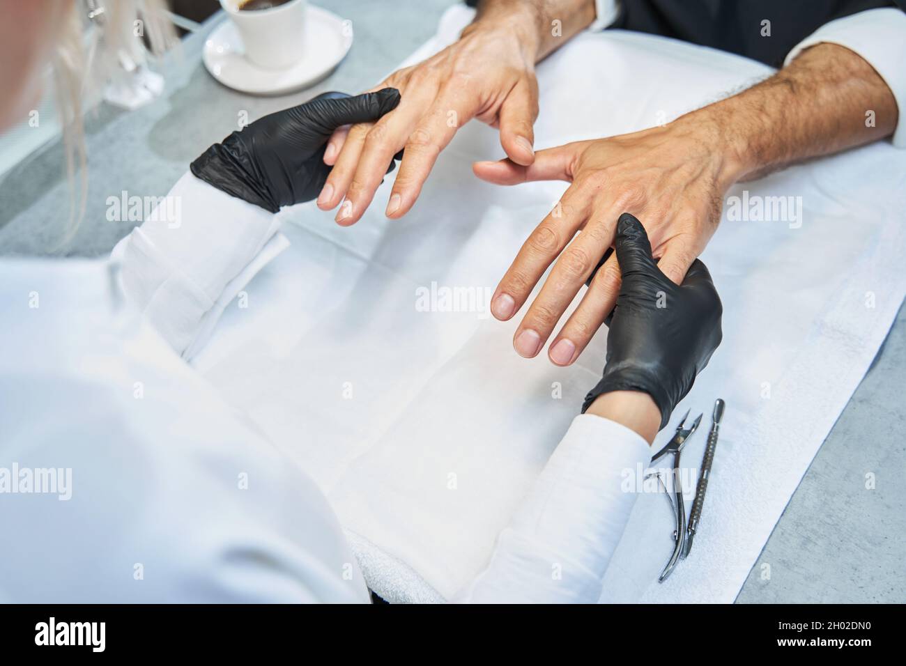 Manicurist taking client hands and inspecting nails Stock Photo - Alamy