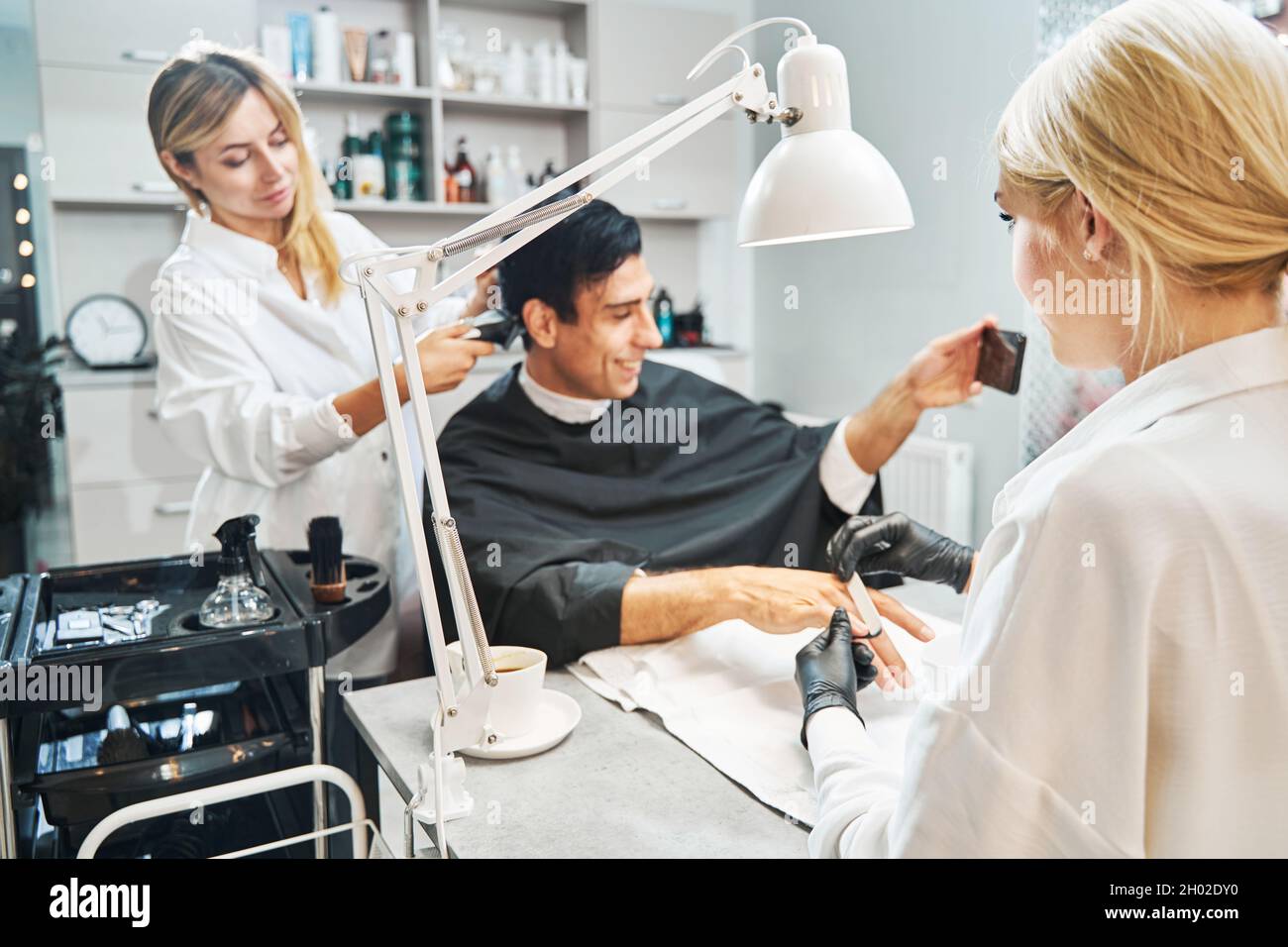 Female with file grinding nails of client with phone Stock Photo - Alamy
