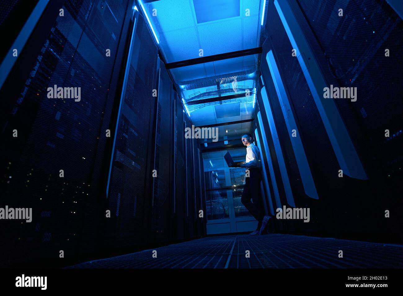 Man network administrator with laptop leaning against server rack Stock ...
