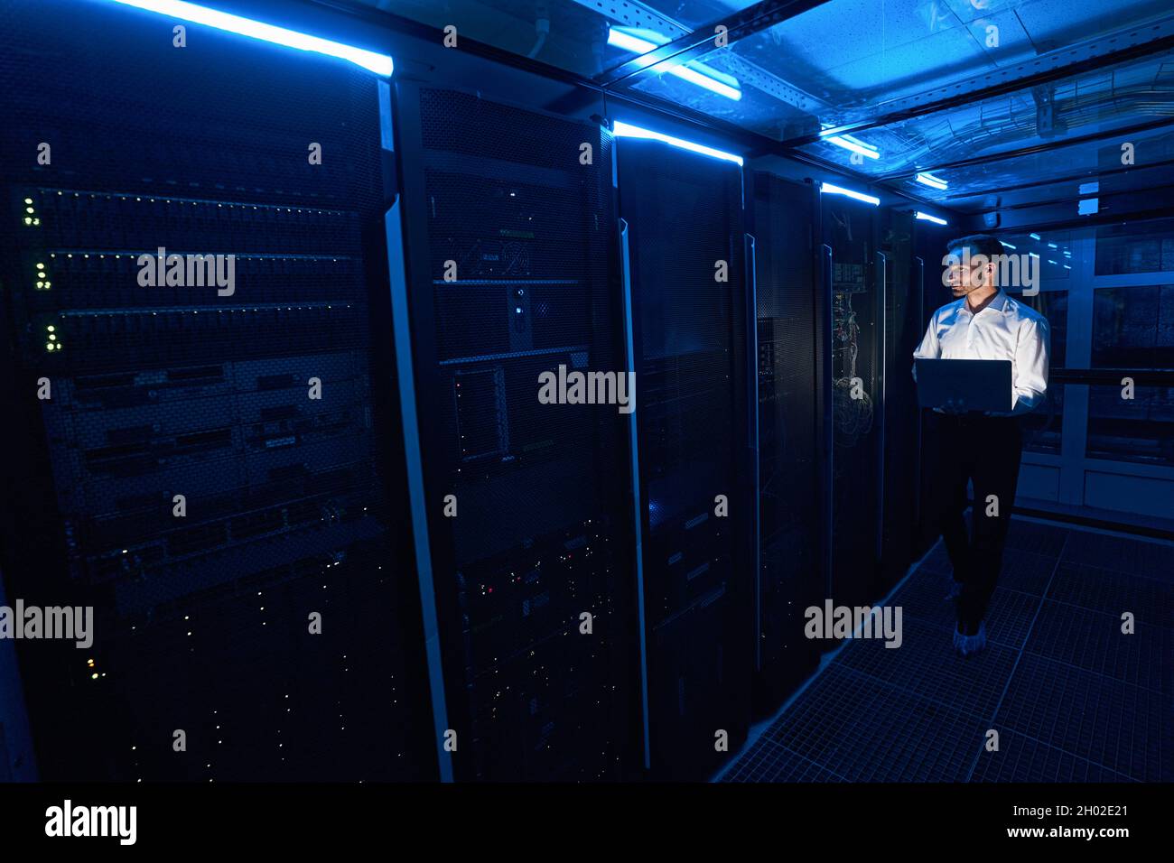 Male server technician walking with laptop in data center room Stock ...